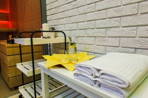 Um banheiro bem organizado com parede de tijolos brancos, uma prateleira com artigos de higiene e um porta-toalhas.