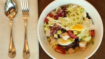Uma salada com diversos ingredientes sobre uma mesa de madeira.