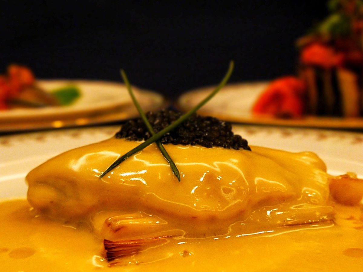 Um prato com molho cremoso e uma guarnição de caviar preto por cima.