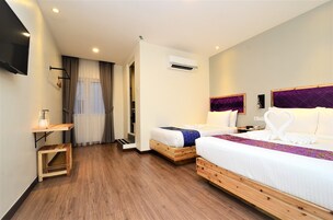 Quarto de hotel com duas camas, televisão, ar condicionado e uma pequena mesa.