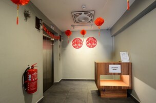 Uma área de recepção com um banco de madeira, um extintor de incêndio e lanternas vermelhas na parede.
