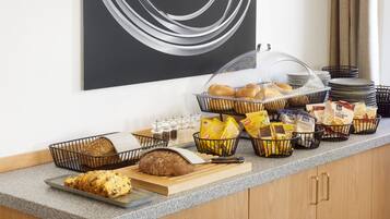Um buffet de café da manhã com pães, doces e acompanhamentos.