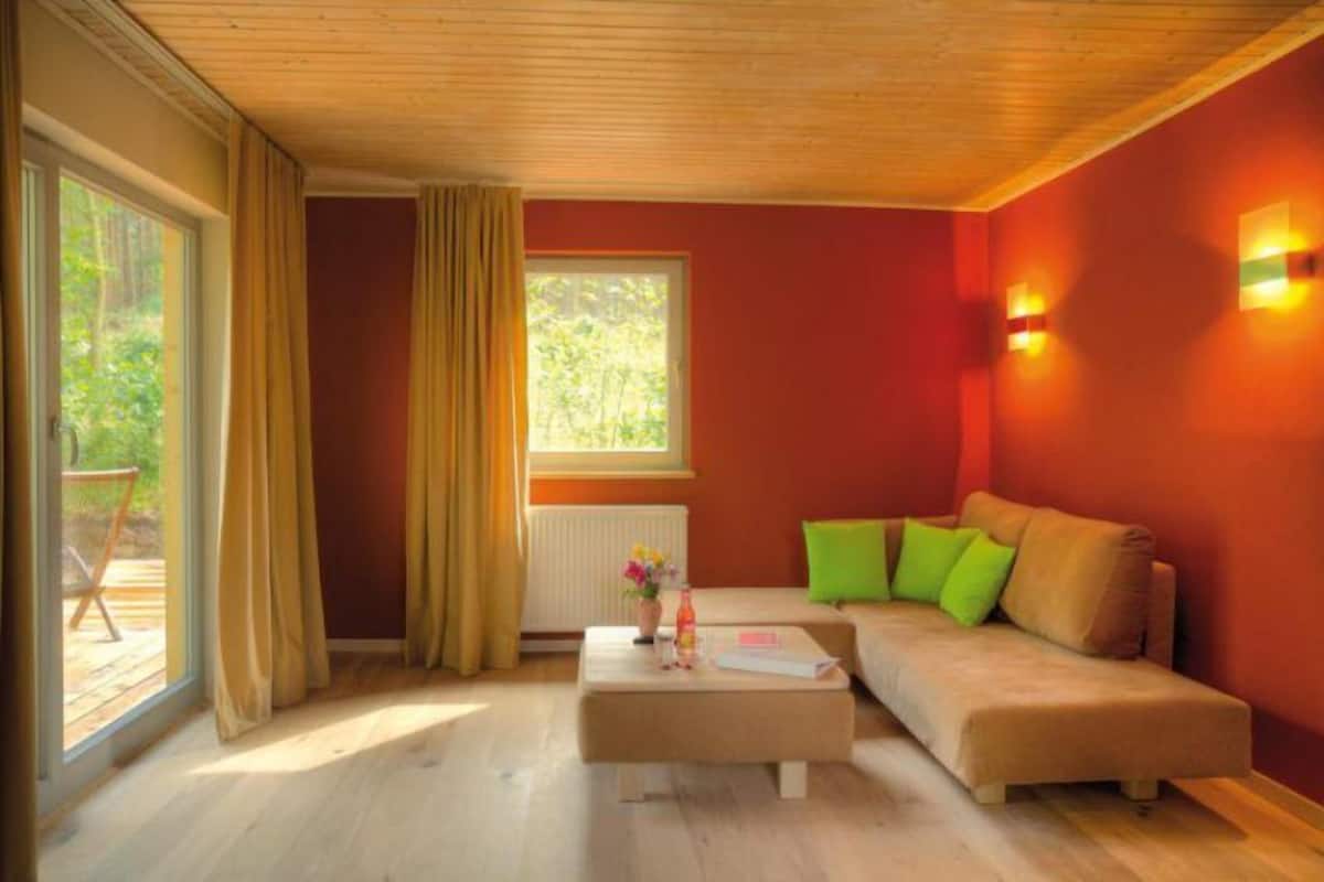 Uma sala de estar aconchegante com um sofá, um banquinho e uma janela com cortinas.
