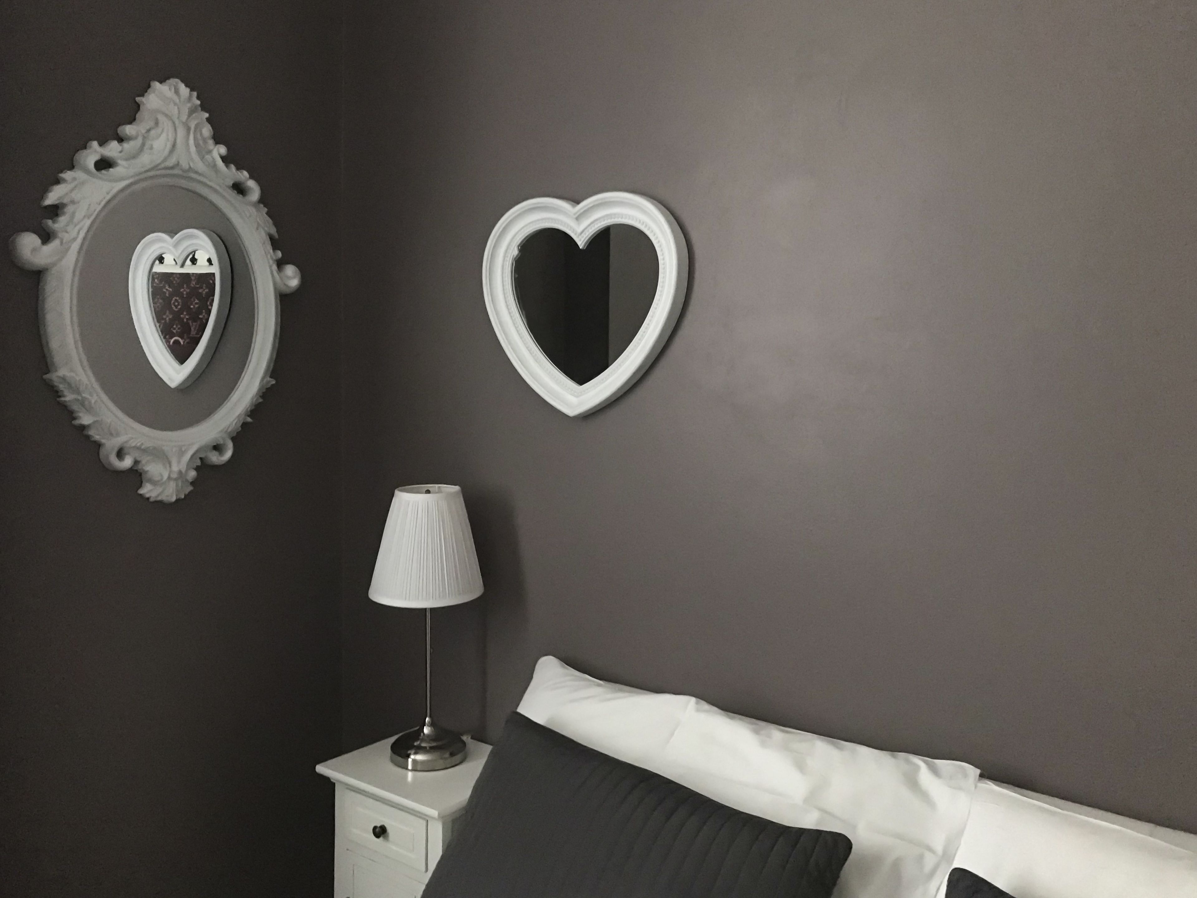 Quarto com uma cama, mesa de cabeceira, luminária e duas decorações na parede.