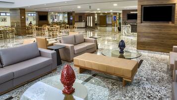Um amplo saguão com piso de mármore, áreas de estar e um balcão de recepção.