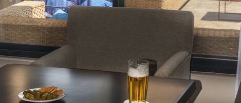 Uma sala de jantar com móveis de vime, um copo de cerveja e um tablet sobre a mesa.