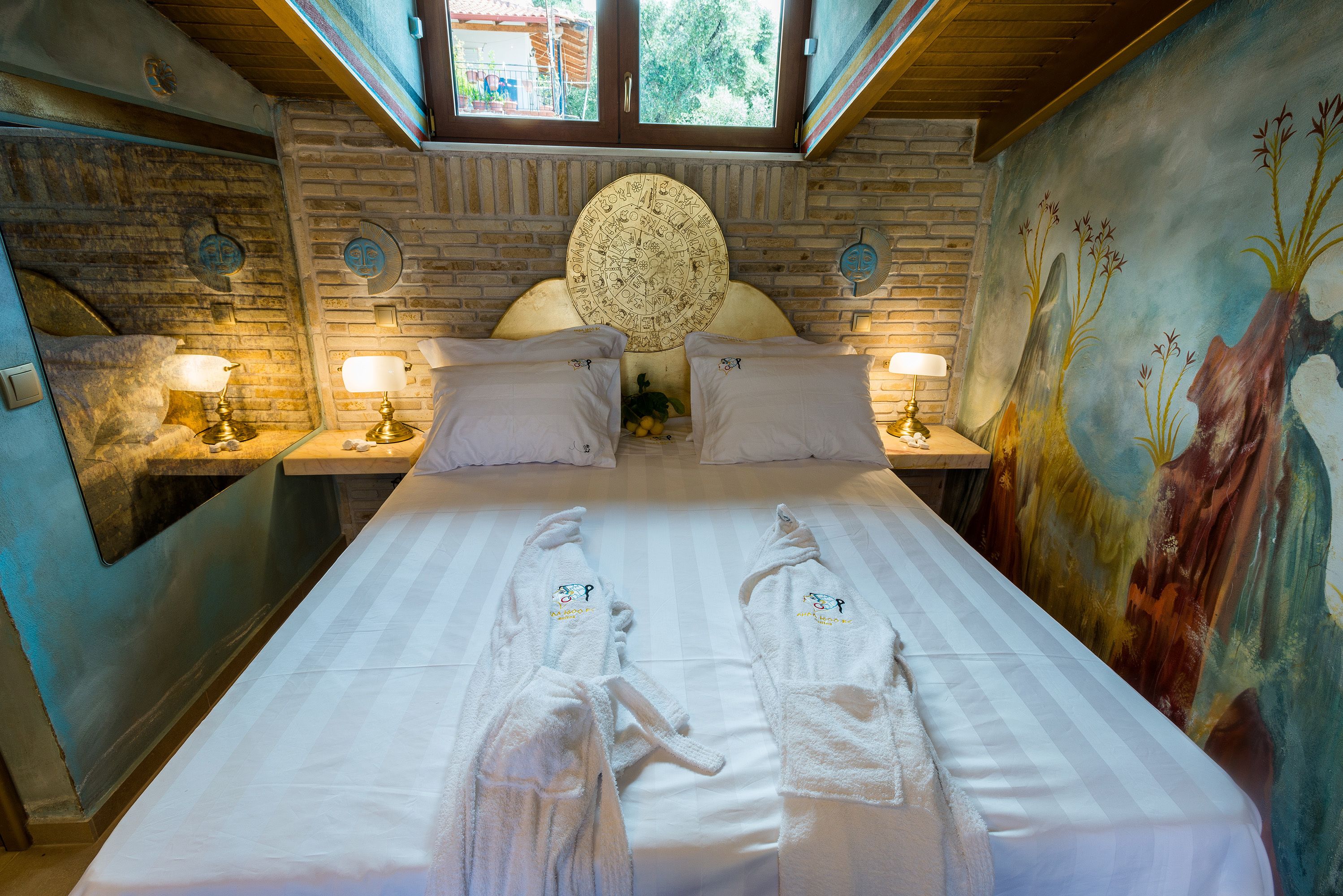Uma cama de casal com duas toalhas brancas, um relógio de parede redondo e um mural na parede.