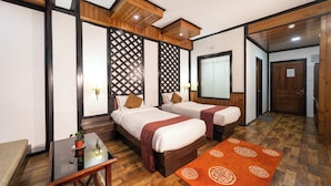 Quarto de hotel com duas camas, teto de madeira, divisória treliçada e piso de madeira.