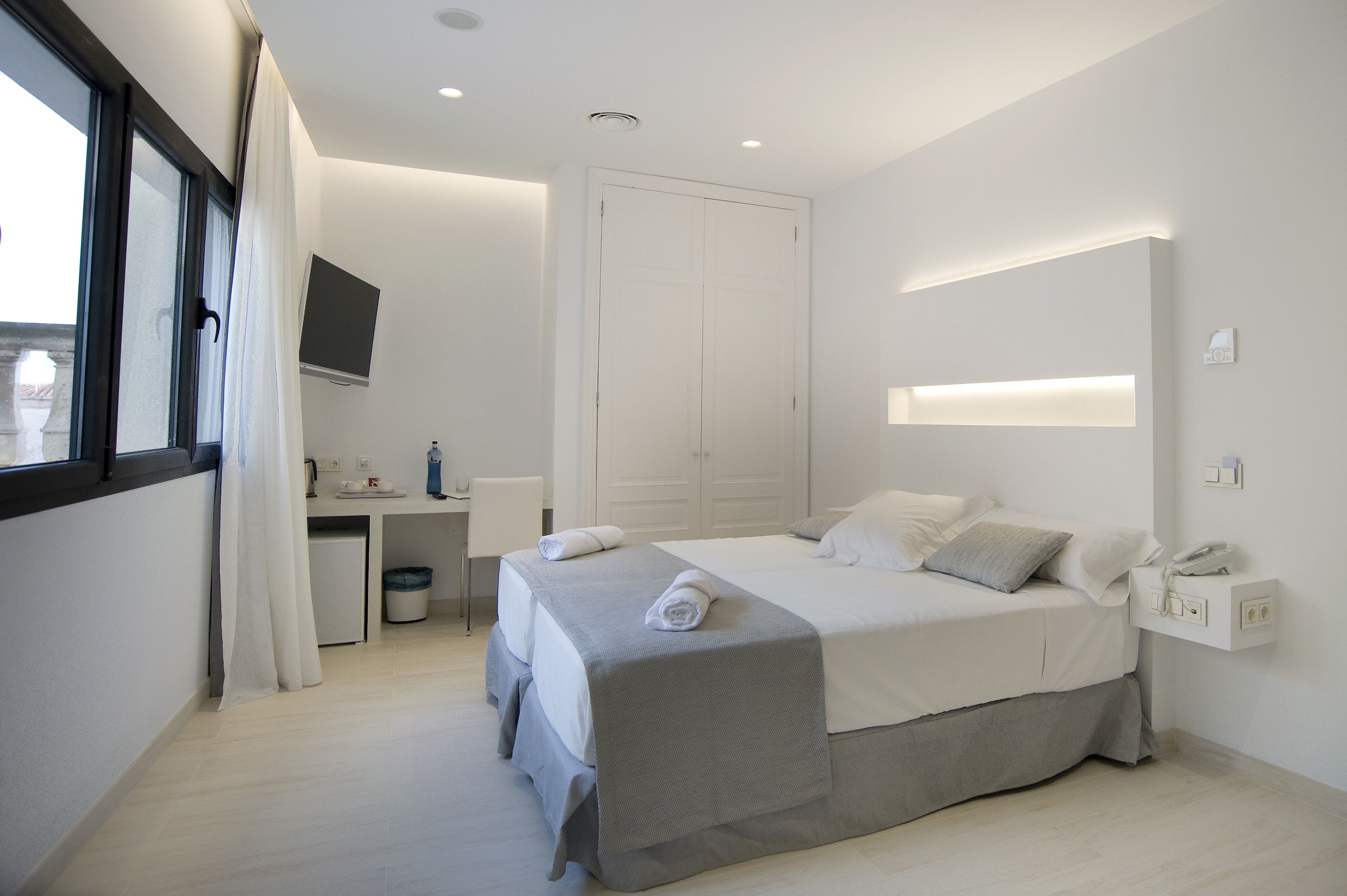 Quarto moderno com cama, mesa de cabeceira e escrivaninha com cadeira.