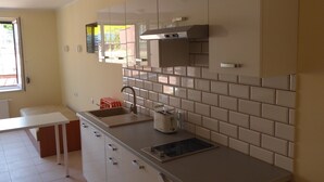 Cozinha moderna com armários brancos, uma pia de aço inoxidável e painel de azulejos.
