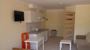 Um espaço compacto com cozinha compacta, mesa de jantar, sofá e uma cama pequena.