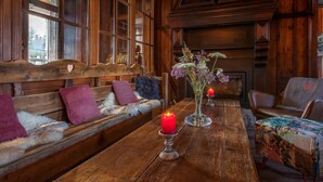 Um quarto aconchegante com um banco de madeira, uma mesa com uma vela e um vaso com flores.