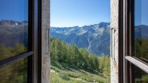 Vista de montanhas através de uma janela com moldura de madeira.