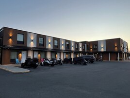 Um hotel moderno com uma fileira de quartos e área de estacionamento.