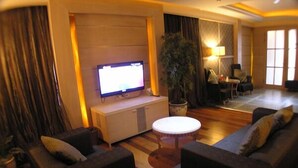 Uma sala de estar com televisão de tela plana, sofá, mesa de centro e um vaso com planta.