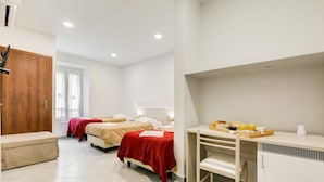 Quarto de hotel com duas camas, uma escrivaninha e uma cadeira.