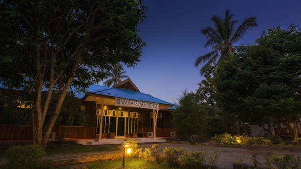 Um hotel com telhado azul e uma placa que diz 'Waisai Beach Hotel'.