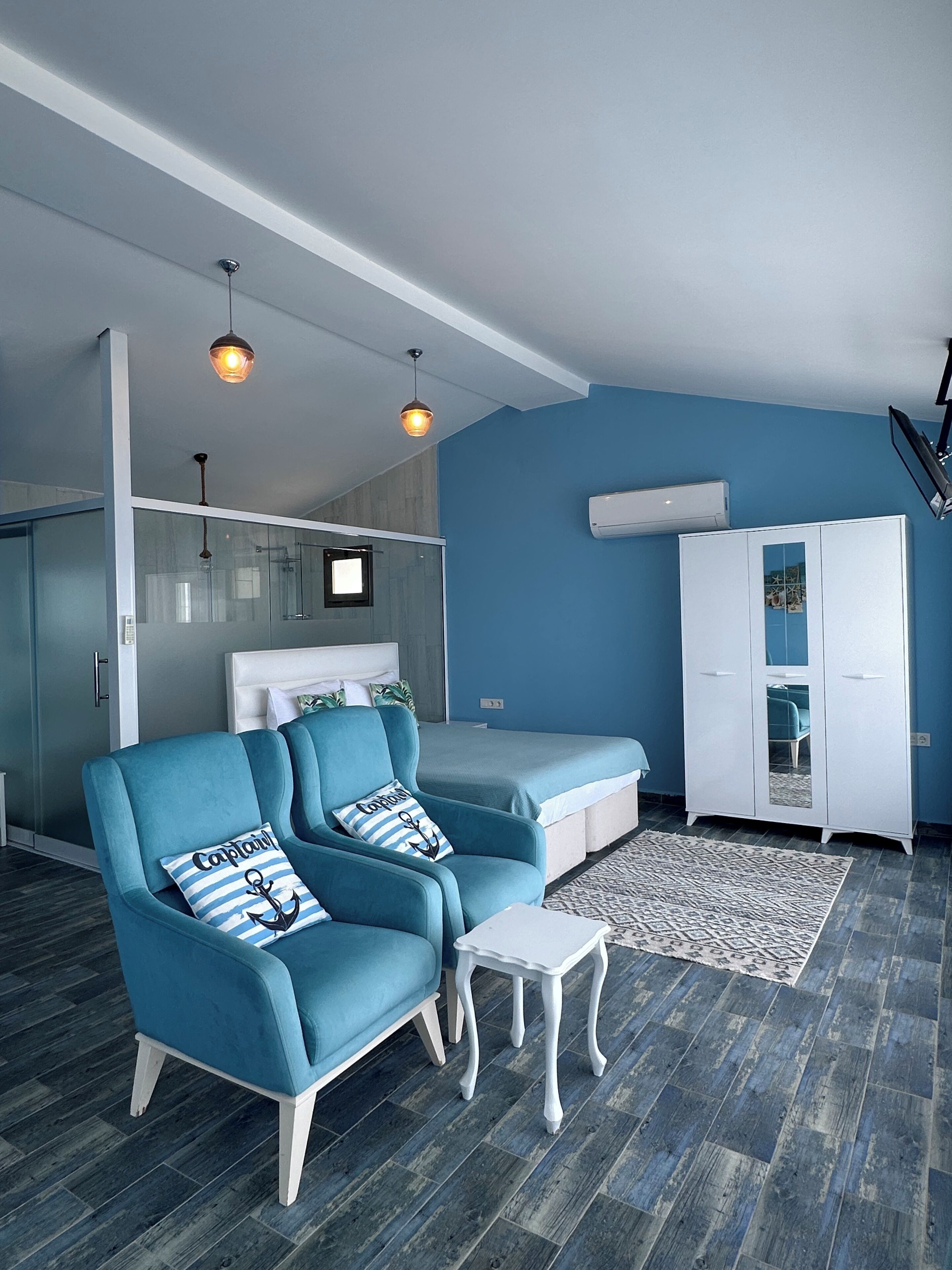 Quarto moderno com sofá azul, armário branco e uma cama.