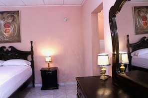Um quarto com cama, mesa de cabeceira, luminárias e um espelho.