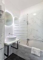 Casa de banho moderna com lavatório de mármore branco, cabine de duche em vidro e um porta-toalhas.