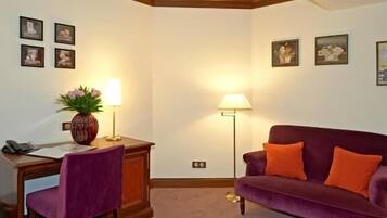 Um quarto com escrivaninha, poltrona roxa, sofá roxo e duas luminárias.