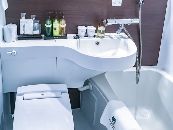 Casa de banho com lavatório branco, banheira e artigos de higiene pessoal no balcão.