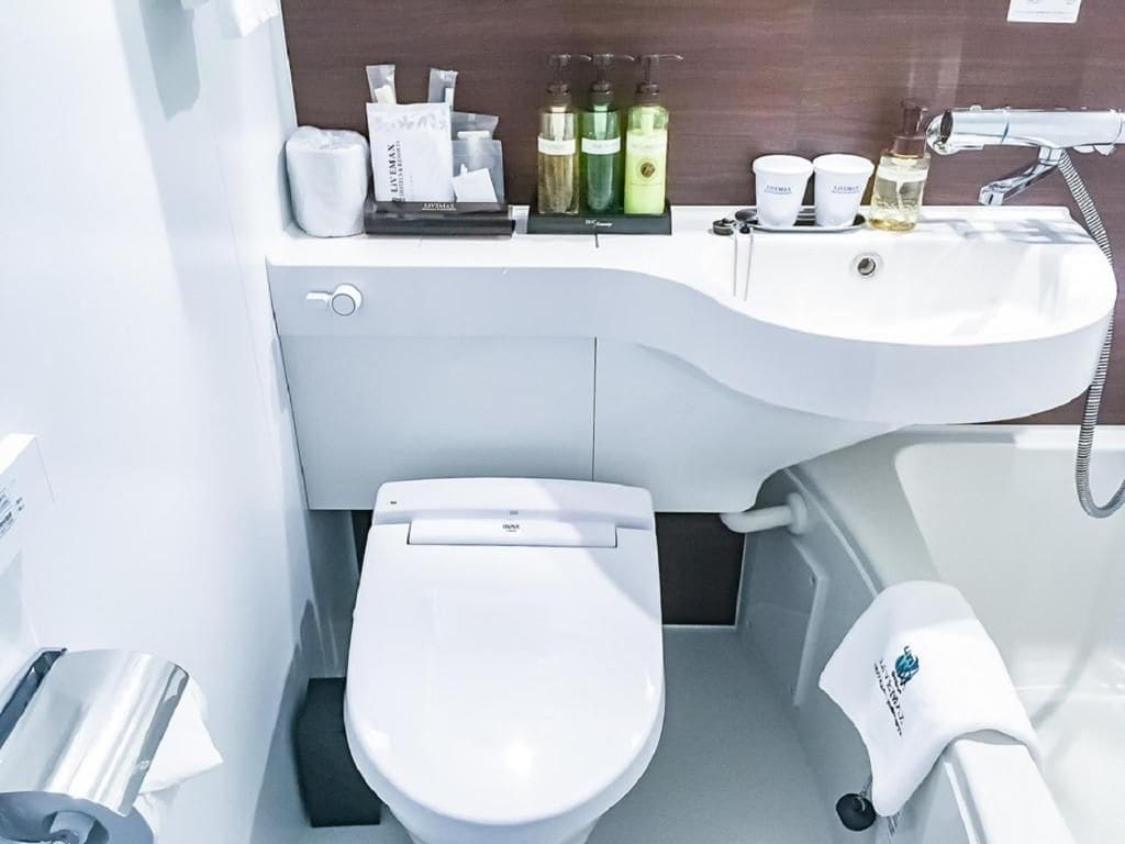Casa de banho moderna com sanita branca, lavatório e diversos artigos de higiene pessoal.
