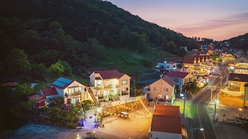 Uma vila numa encosta, com mistura de edifícios residenciais e comerciais, destacando-se um hotel com varanda e área de estar ao ar livre.