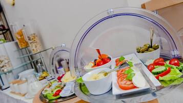 Buffet com diversos pratos, incluindo saladas, frutas e legumes.