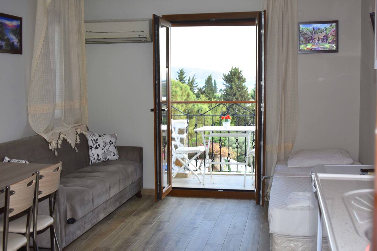 Quarto com varanda, sofá, mesa de jantar e cama.