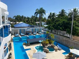 Resort com várias piscinas, espreguiçadeiras e um edifício grande com telhado azul.