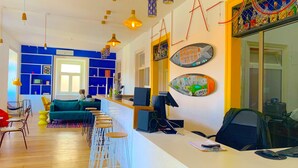 Uma sala de estar moderna com um sofá, uma mesa de centro e uma televisão. Há também vários banquinhos e um espaço bar com balcão.