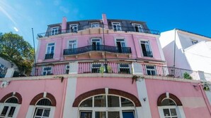 Um edifício rosa de vários andares com janelas em arco e varandas.