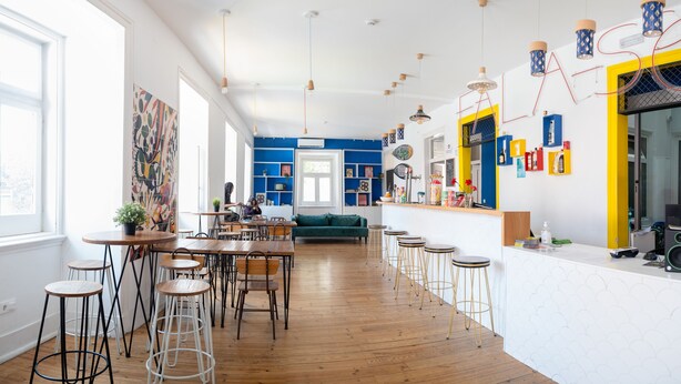 Uma cozinha moderna com piso de madeira, uma ilha central, banquetas e um espaço de estar com sofá.