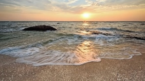 Uma praia com ondas e um pôr do sol.