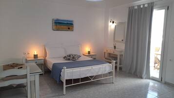 Quarto com cama, mesas de cabeceira, penteadeira, espelho e vista para o exterior.