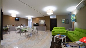 Uma sala de estar moderna com área de jantar, cozinha e um sofá verde.