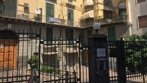 Um edifício com várias andares, varandas, portão e um poste de luz.