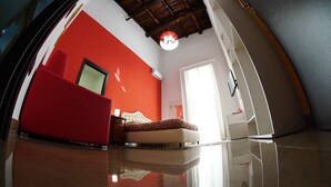 Quarto com parede vermelha, cama branca e teto de madeira.