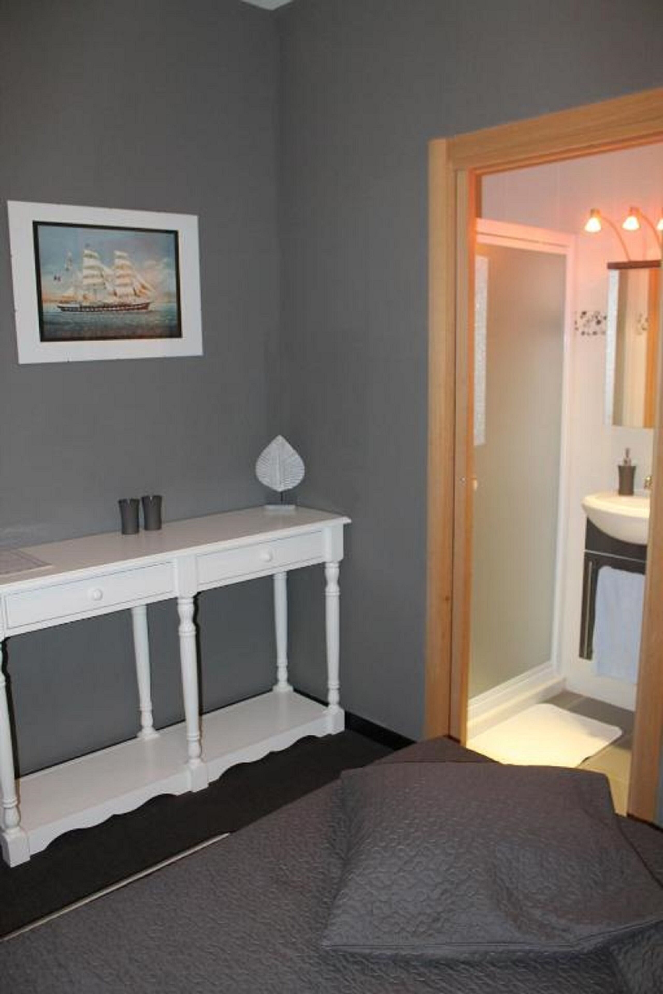 Uma casa de banho com um lavatório branco, um espelho e um quadro emoldurado na parede.