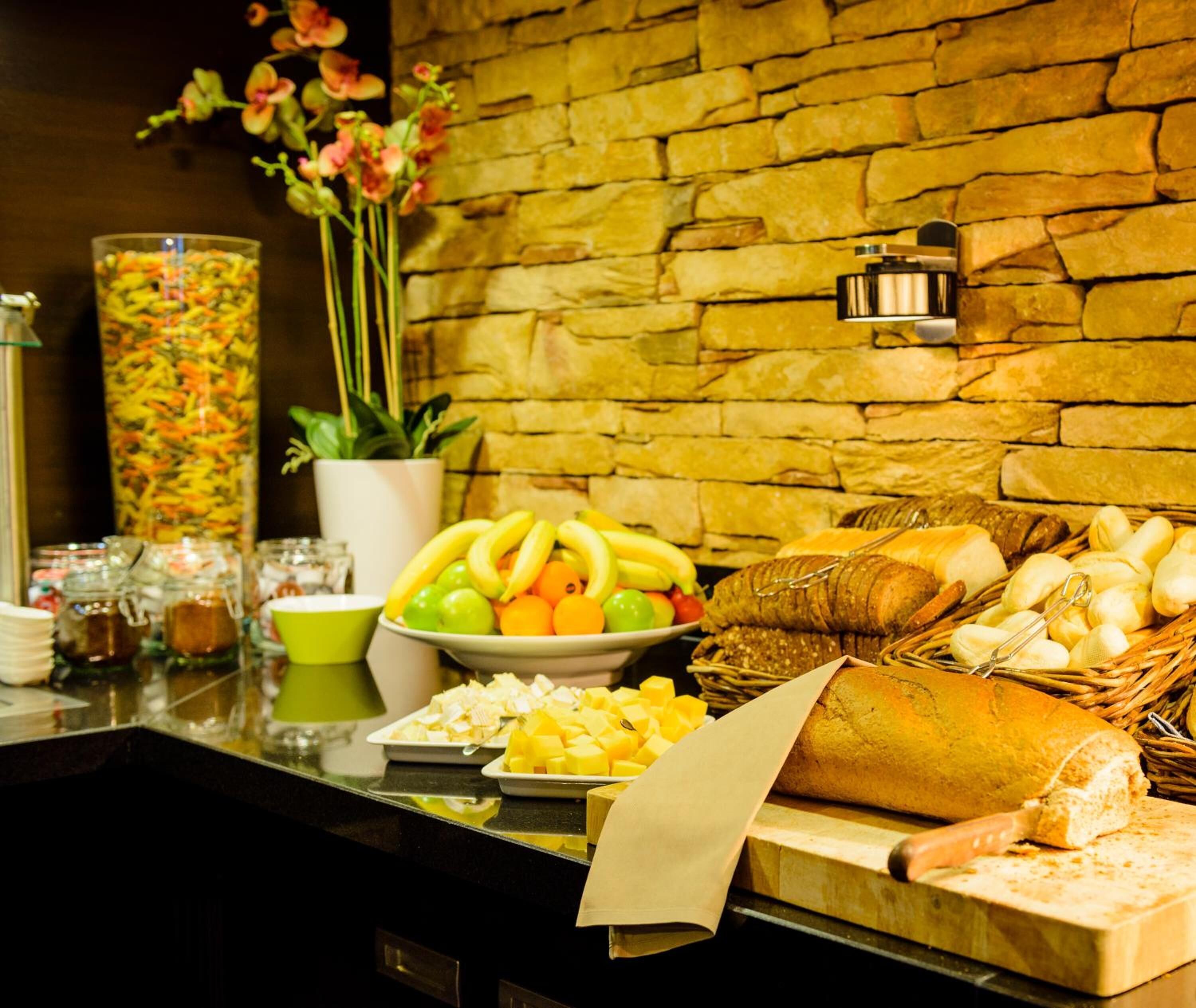 Disposição de buffet com diversos alimentos, incluindo frutas, pão e acompanhamentos.