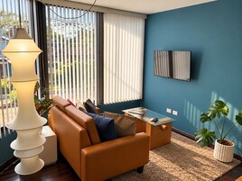 Uma sala de estar moderna com sofá, mesa de centro e TV na parede.