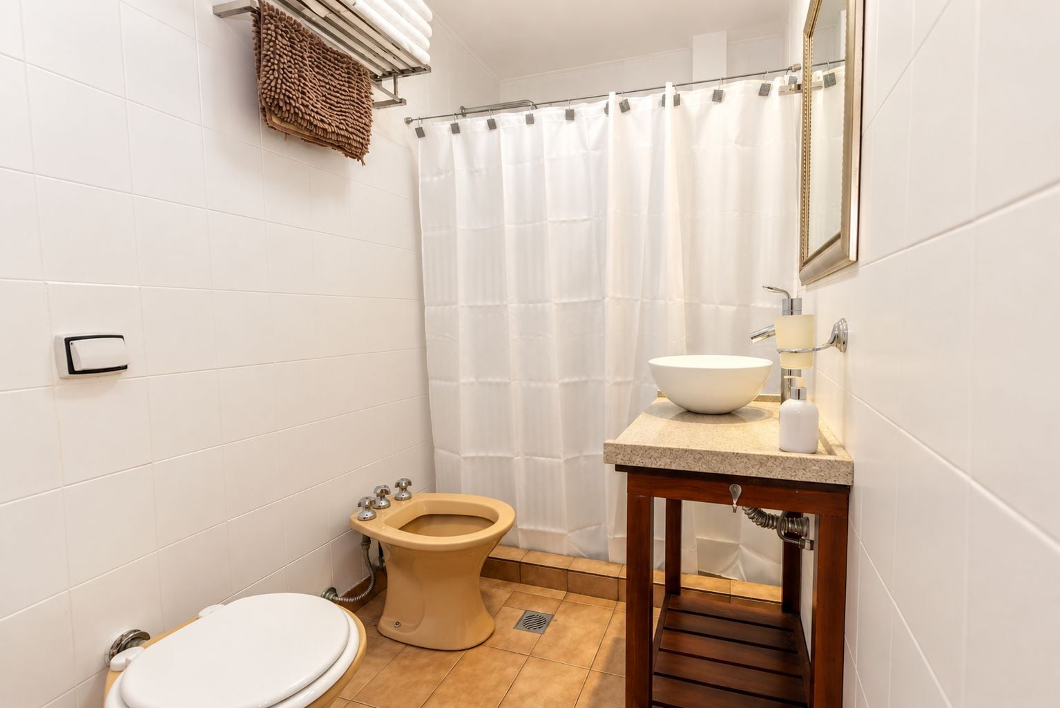 Casa de banho com sanita, bidé e lavatório com espelho.