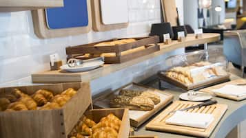 Vitrine de pastelaria com diversos produtos de panificação e uma faca sobre uma tábua de corte.