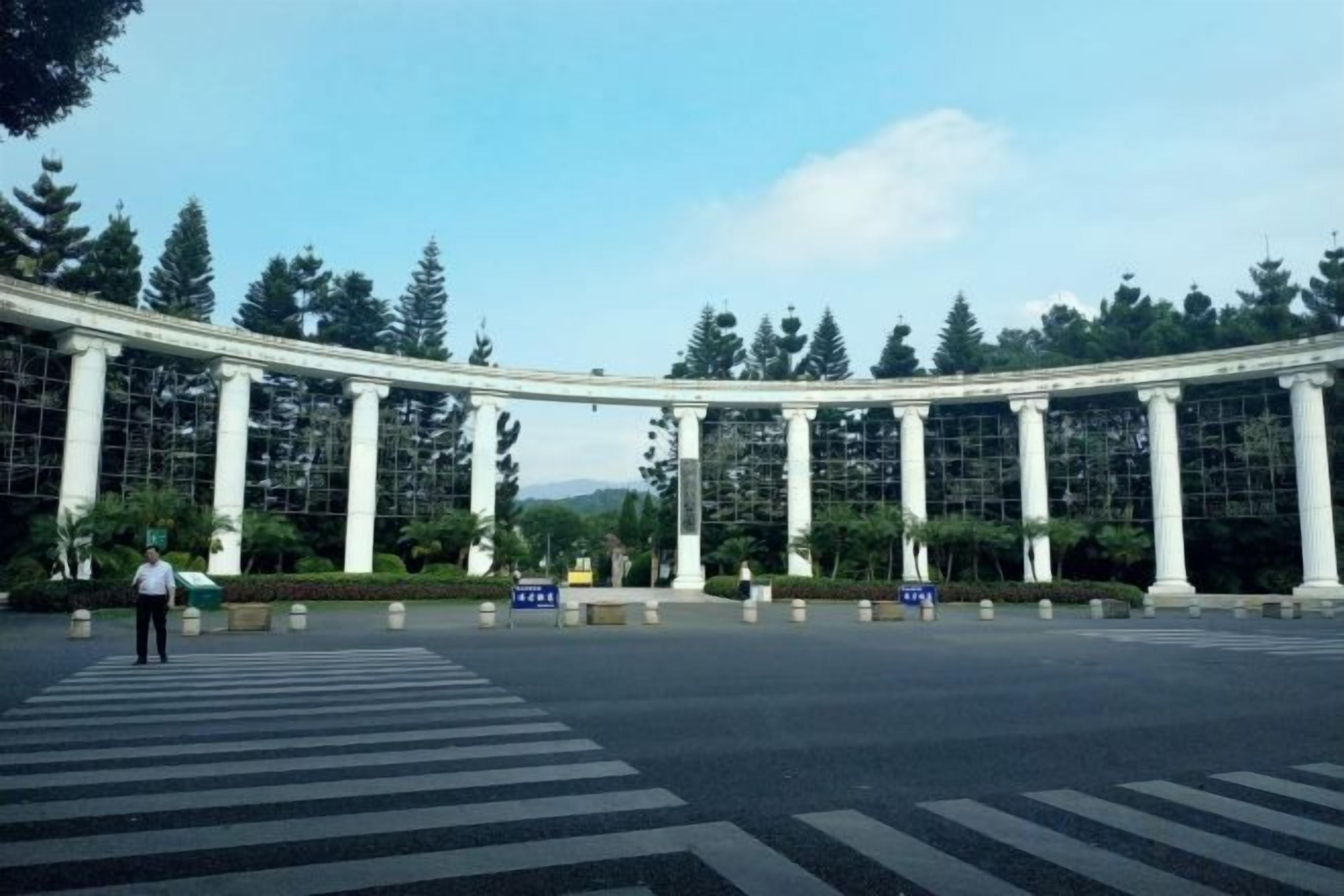 Um edifício grande com uma praça central aberta, rodeado por árvores e colunas.