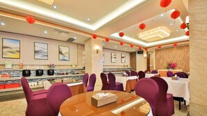 Restaurante com mesas redondas, cadeiras roxas e lanternas vermelhas.
