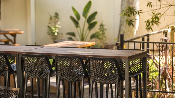 Uma área de pátio com uma mesa de madeira e cadeiras de metal.