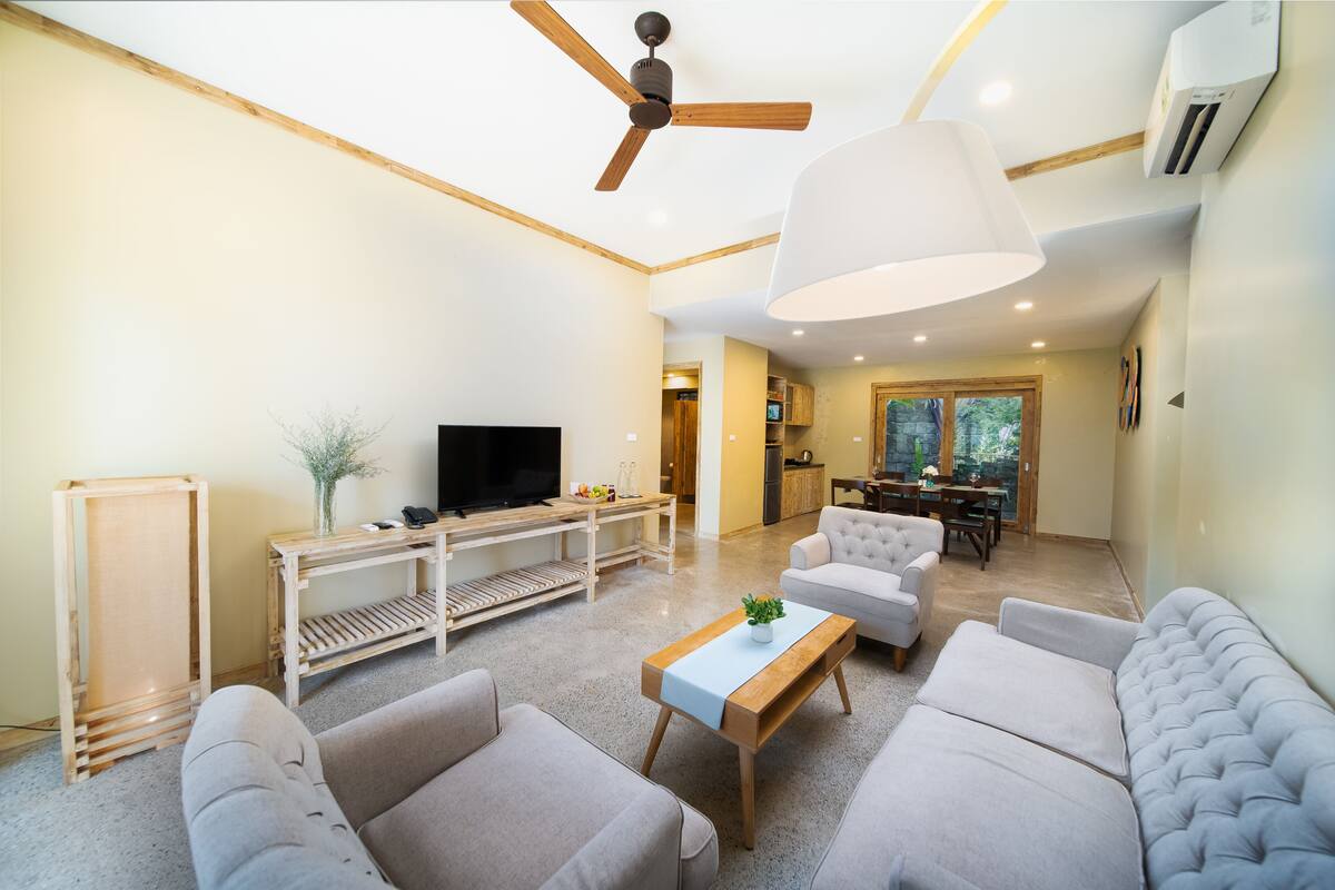 Uma sala de estar moderna com televisão de tela plana, mesa de centro de madeira e ventilador de teto.