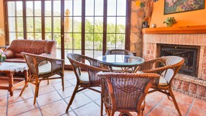 Uma área de pátio acolhedora com móveis de vime, lareira e uma grande janela com vista para as montanhas.