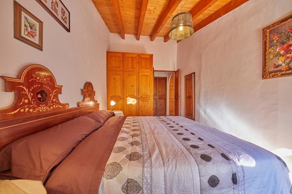Quarto com cama de madeira, guarda-roupa espaçoso e um quadro na parede.